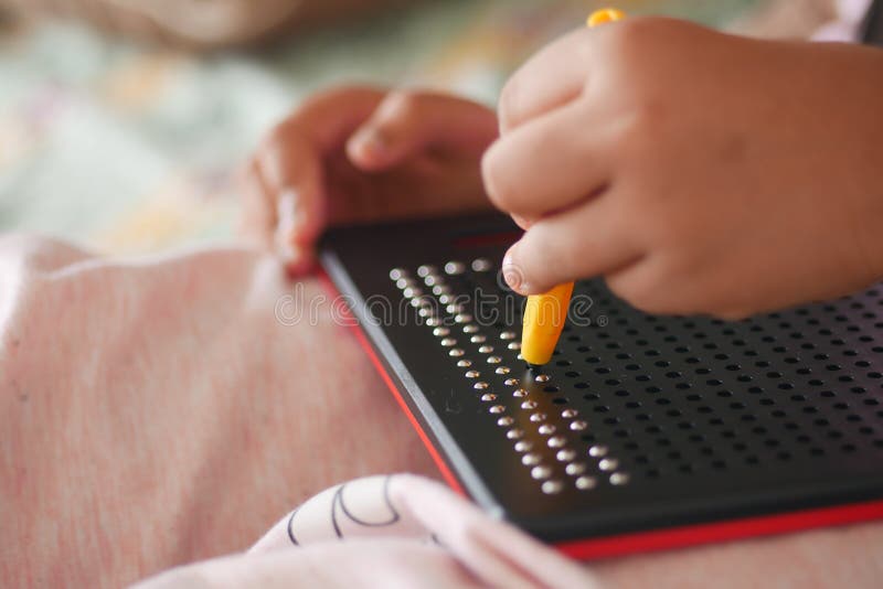 Child Engaged in Creative Activity with a Dot-matrix Board at Home ...