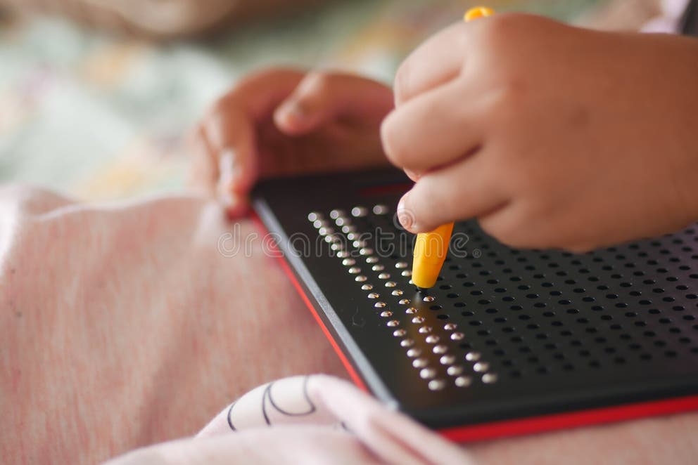 Child Engaged in Creative Activity with a Dot-matrix Board at Home ...