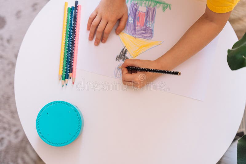A Child Draws at the Table with a Black Pencil on a Sheet of Paper ...