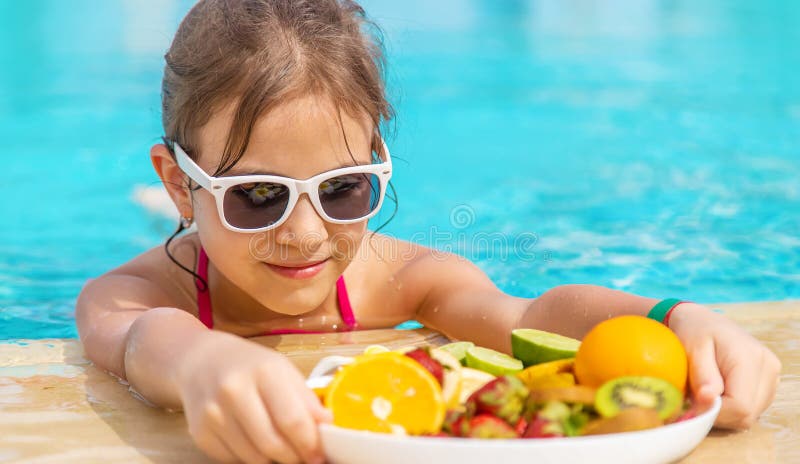 The Child Eats Fruit Near the Pool. Selective Focus Stock Photo - Image ...