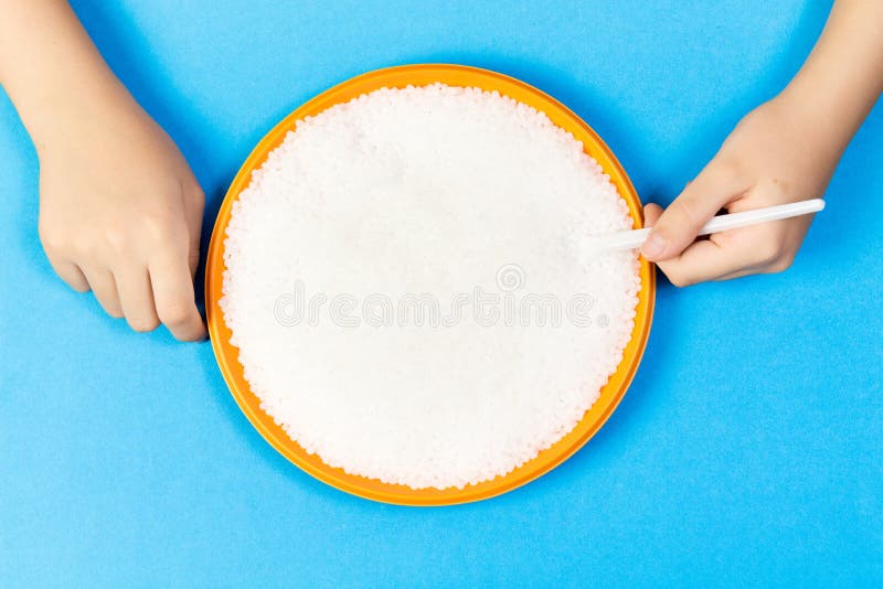 A Child Eats Plastic Pellets from a Plate .Concept of Environmental ...