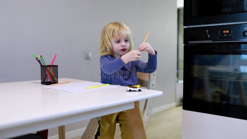 Child Engaging in Creative Drawing Activity Using Crayons and Toys in a ...