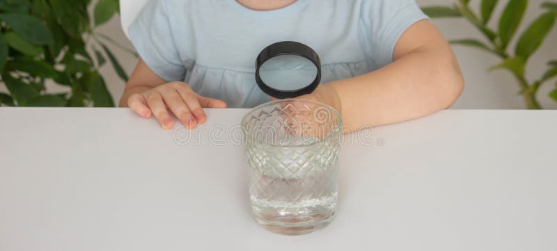 Child Examines and Examines Water Under a Magnifying Glass. Selective ...