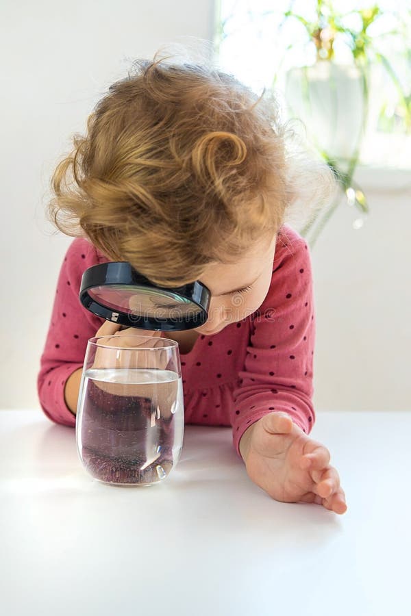 The Child Examines the Water Under a Magnifying Glass. Selective Focus ...