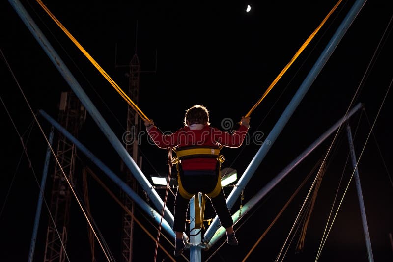 Child at a Fair Jumping on a Bungee Trampoline during the Night Stock ...