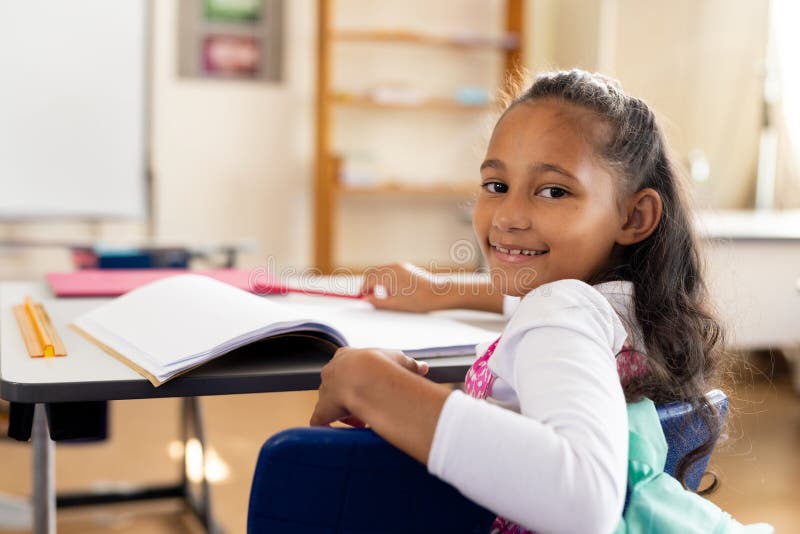 Child Girl Sitting Facing Camera at School Desk, with Notebook and ...
