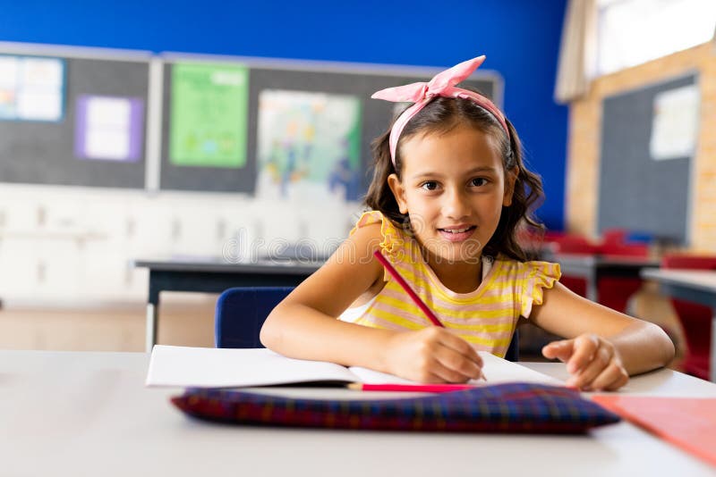 Child Girl Student Writing in Elementary Classroom with Blue Wall, Open ...