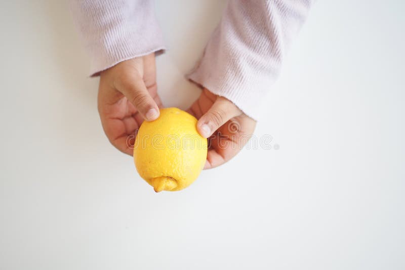 Child Hand Holding a Lemon on White Surface Stock Image - Image of ...