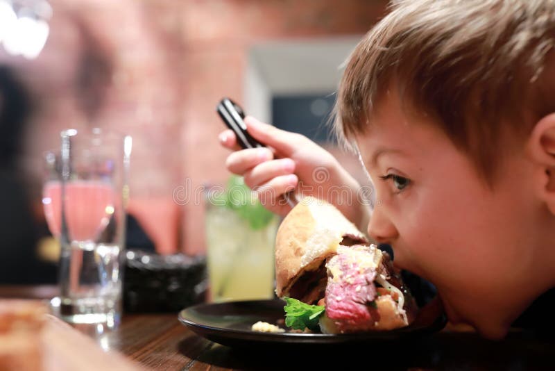Child Has Burger in Dark Restaurant Stock Photo - Image of fast, eating ...