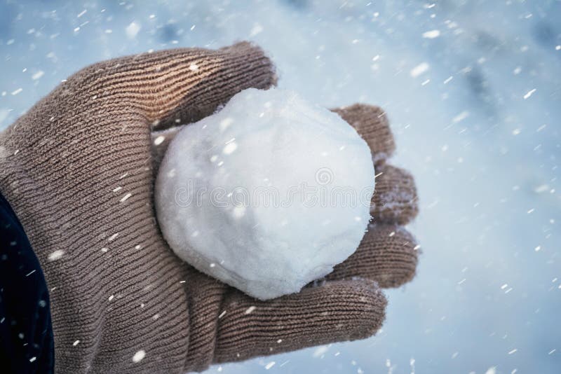 The Child Holds a Snowball in His Hand during a Snowfall Stock Photo ...