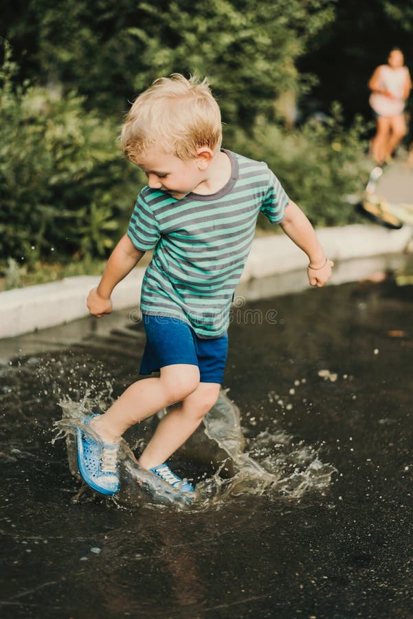 Little Boy Jumping in a Puddle in Summer Stock Photo - Image of flood ...
