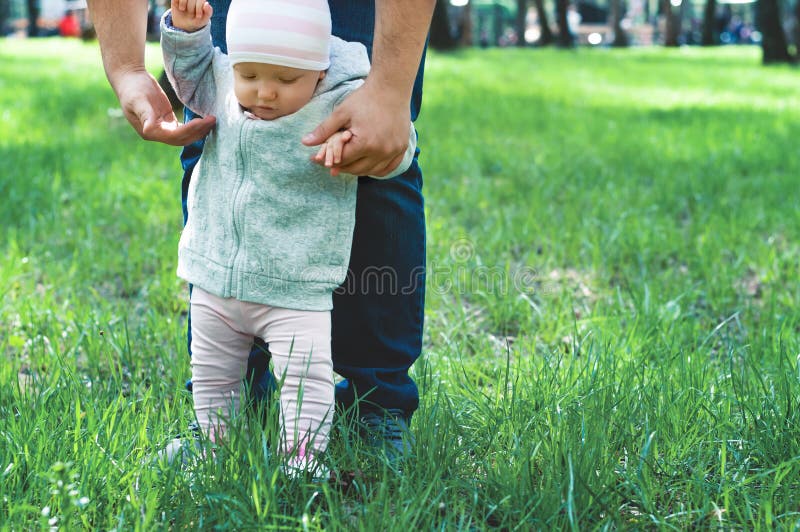 A Child Learns To Walk with Dad on the Grass in the Park. Spring Walk ...