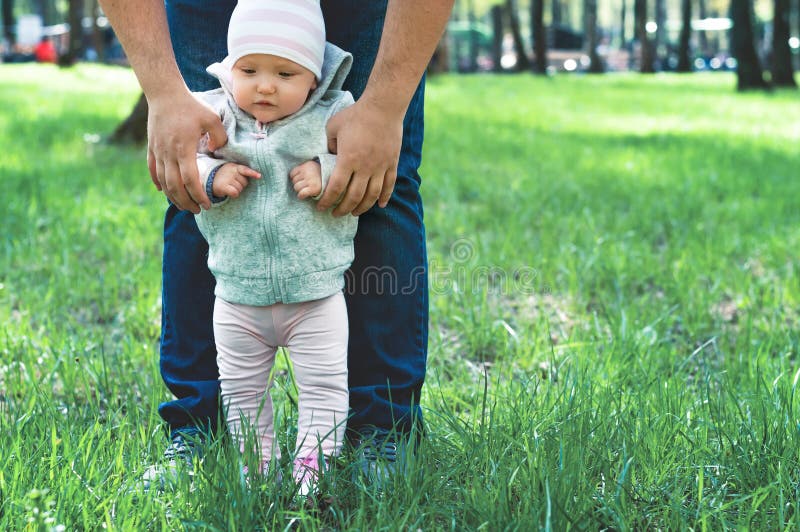 A Child Learns To Walk with Dad on the Grass in the Park. Spring Walk ...