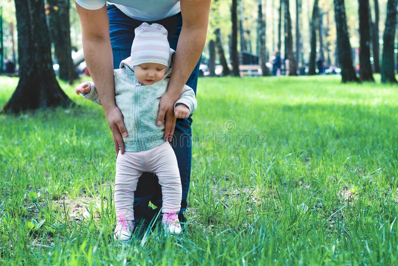 A Child Learns To Walk with Dad on the Grass in the Park. Spring Walk ...