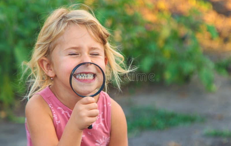A Child Looks through a Magnifying Glass in Nature. Selective Focus ...