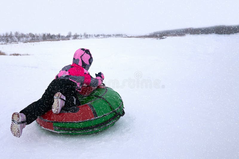 A Child Lying on His Stomach on an Inflatable Sled Slides Down a Snow ...