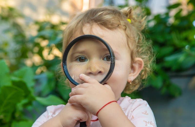 A Child with a Magnifying Glass is Studying the World. Selective Focus ...
