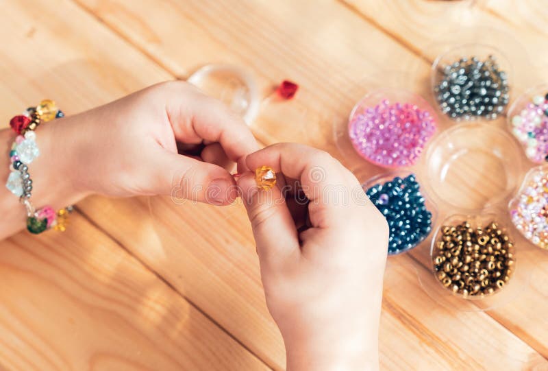 The Child Makes Jewelry with His Own Hands, Stringing Colorful Beads on ...