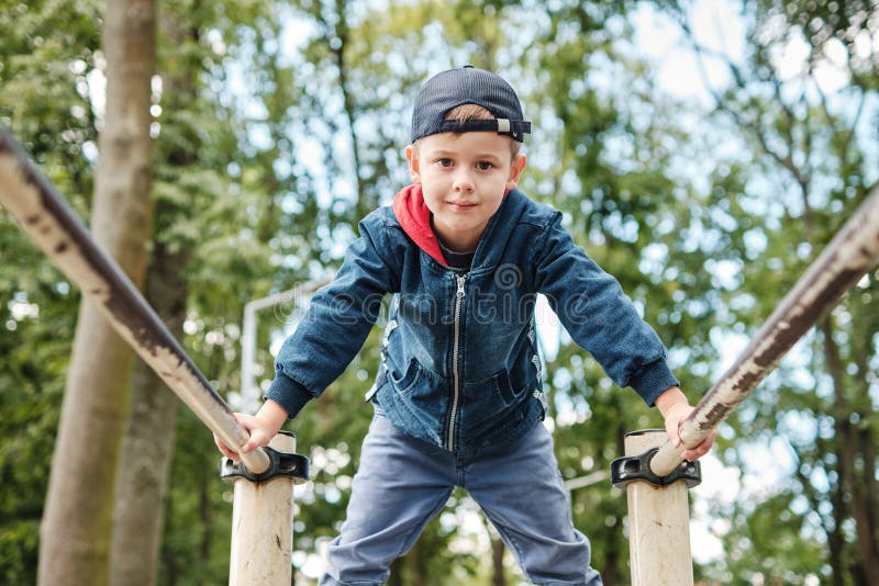 The Child Performs Exercises on Parallel Bars on the Street. Active ...