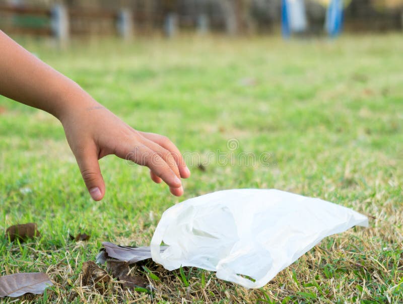 A Little Child Picking Up the Garbage and Putting it in a Black Garbage ...