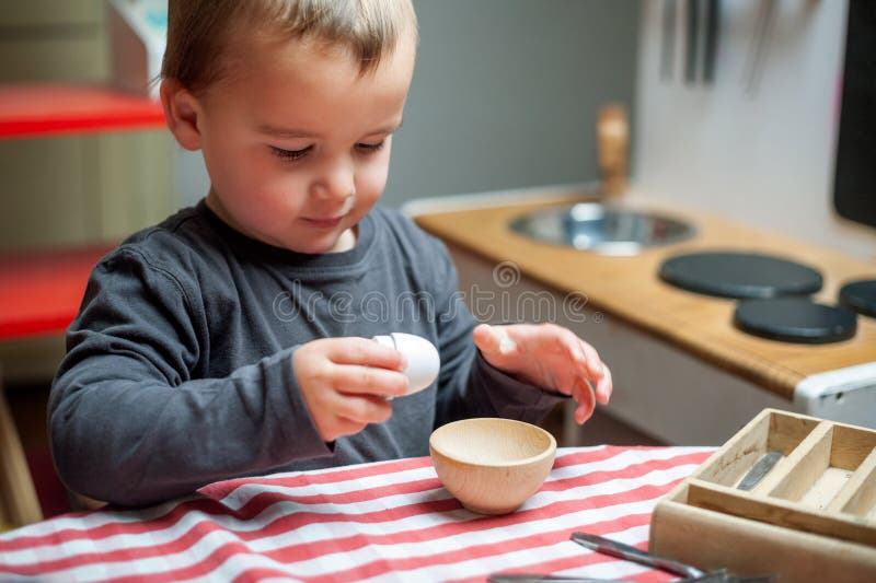 Child Playing at Cooking by Breaking a Wooden Egg in a Bowl. Stock ...