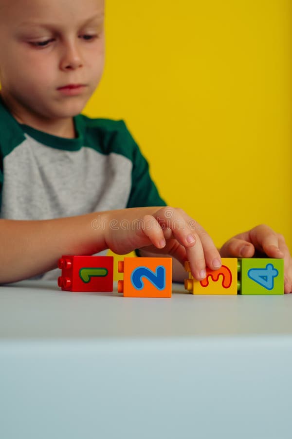 The Child Playing with Cubes with Colorful Numbers on the Table. on a ...