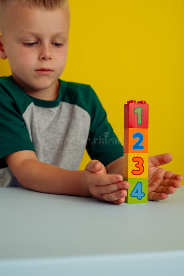 The Child Playing with Cubes with Colorful Numbers on the Table. on a ...
