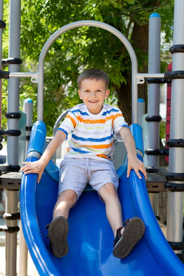 A Child is Playing on an Outdoor Playground. an Active Boy Rides Down a ...