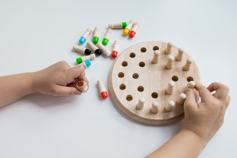 Child Playing Peg Board Game with Colorful Pieces on White Surface ...
