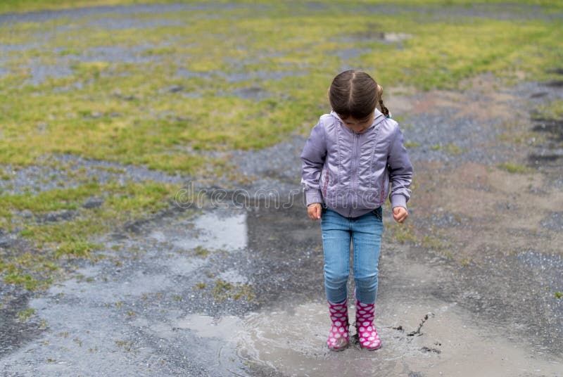The Child Playing in a Puddle Stock Photo - Image of holding, jeans ...