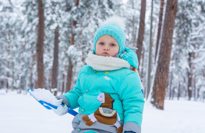 A Child is Playing in a Winter Park, Scooping Snow with a Shovel Stock ...
