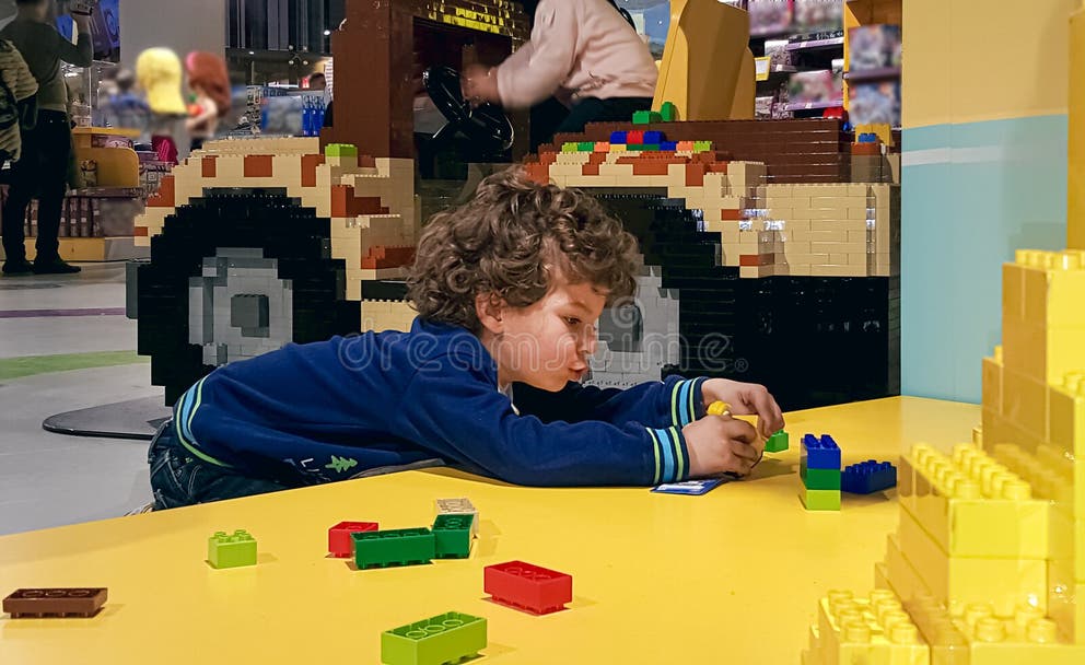 A Child Plays with a Construction Set Made of Blocks in the Play Area ...