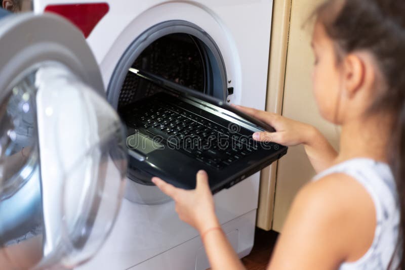 Child Washes Laptop in Sink on Kitchen. Wearing Red Apron and Cook Hat ...