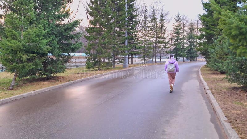 A Child Rides a Scooter in the Spring, in the Park, Back View Stock ...