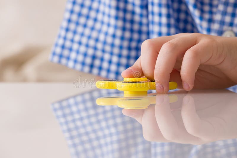 Child`s Hand Spinning a Fidget Spinner Device. Playing with a Yellow ...