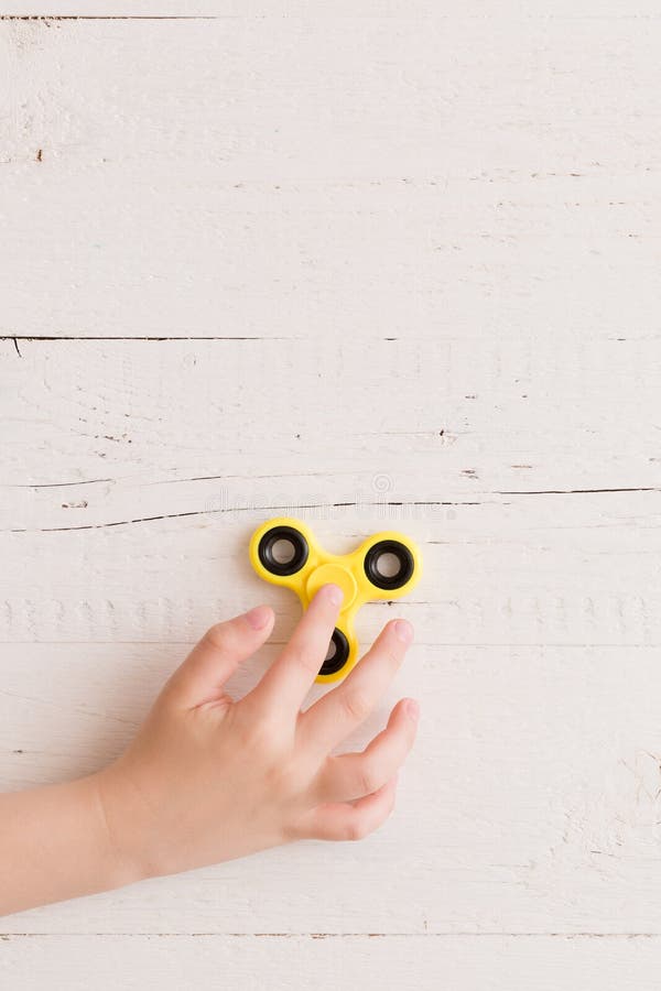 Child`s Hand Spinning a Fidget Spinner Device. Top View Stock Image ...