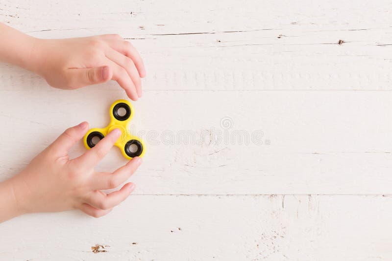Child`s Hand Spinning a Fidget Spinner Device. Top View Stock Photo ...