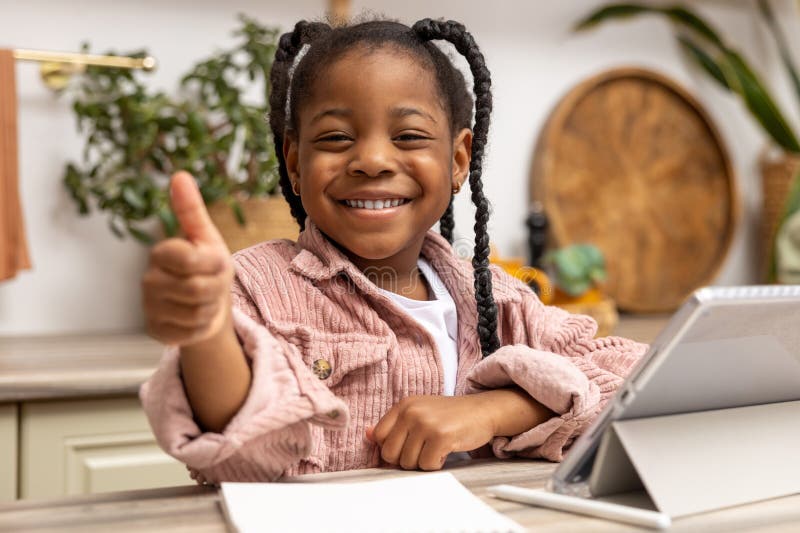 Child Siting at Table Completing Her Schoolwork with the Help of Her ...