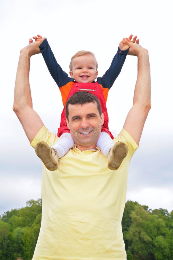 Child Sits at Father on Shoulders with Lifted Hand Stock Photo - Image ...