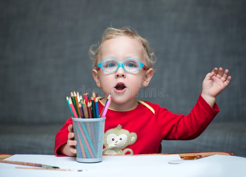 A Child Sitting at a Desk with Paper and Colored Pencils Stock Image ...