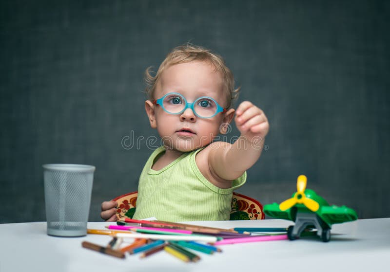 A Child Sitting at a Desk with Paper and Colored Pencils Stock Image ...