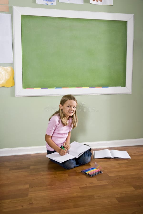 Child Sitting on Floor Writing in Classroom Stock Image - Image of ...