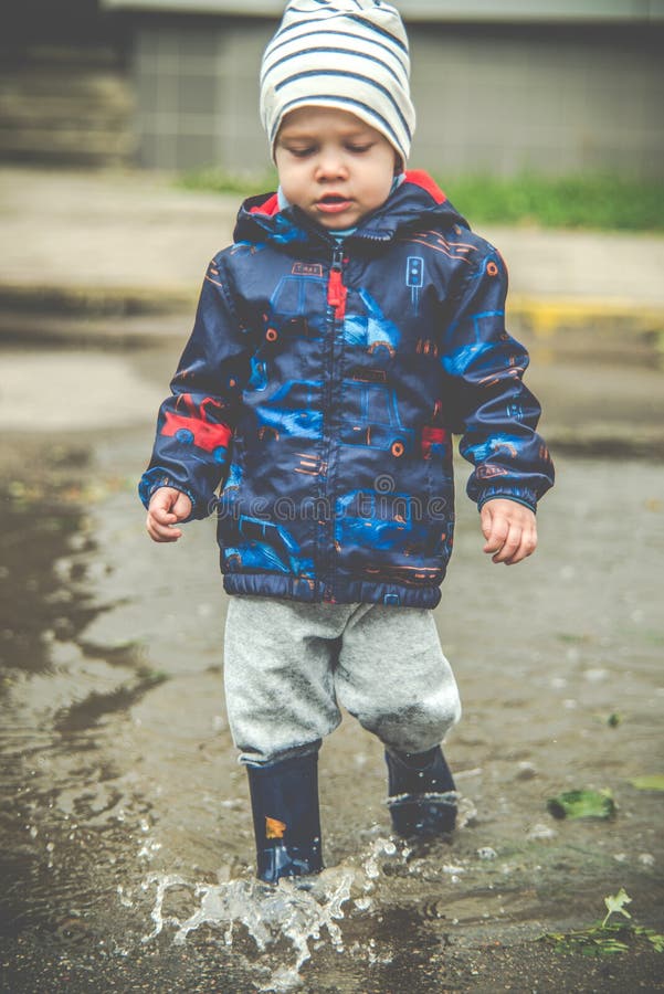 Child splashes puddle stock photo. Image of outdoors - 152498344