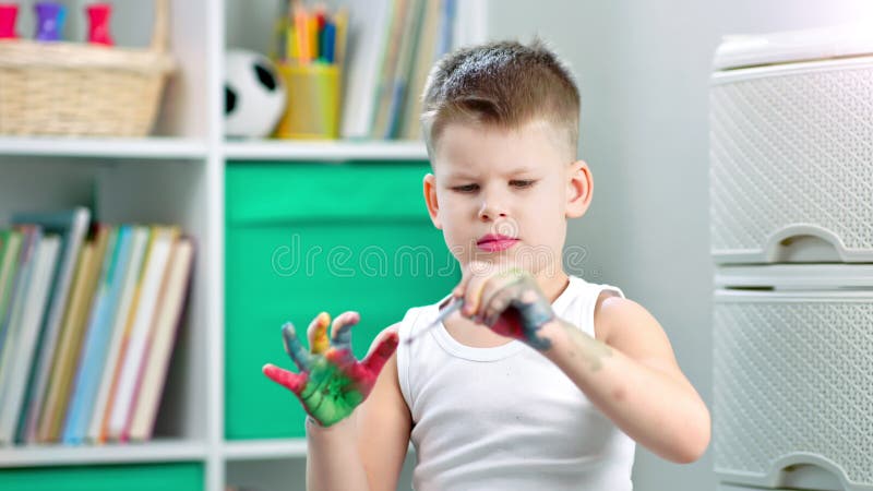 A Child Student is Drawing Something Using a Paintbrush and His Hands ...