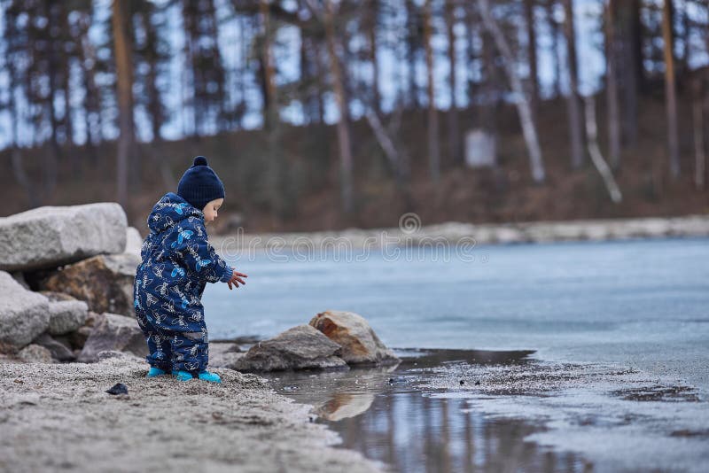 A Child Throws Stones into the Water Stock Photo - Image of standing ...