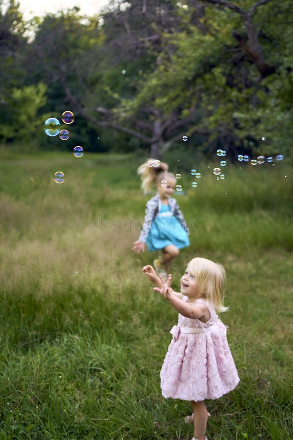 Child and Toddler, Sisters, Catching Bubbles in the Garden Stock Image ...
