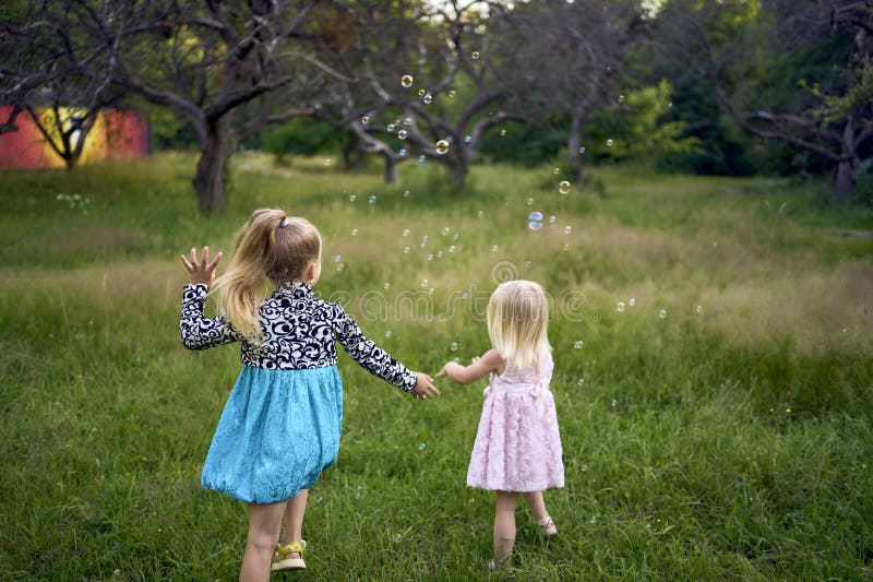 Child and Toddler, Sisters, Catching Bubbles in the Garden Stock Image ...