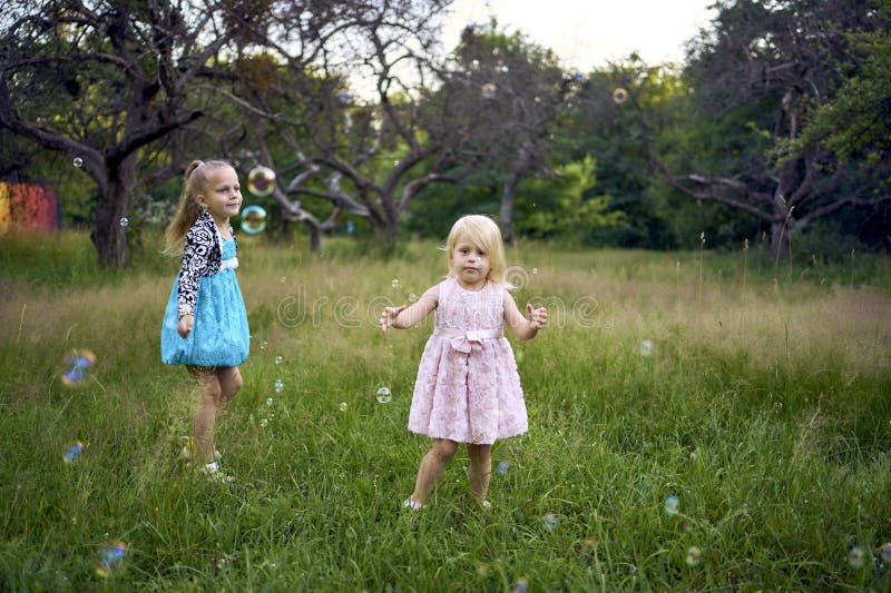 Child and Toddler, Sisters, Catching Bubbles in the Garden Stock Image ...