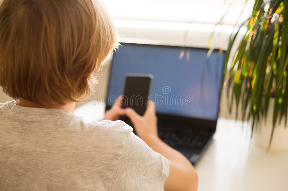 Child Using a Phone while Sitting at a Computer Desk Stock Photo ...