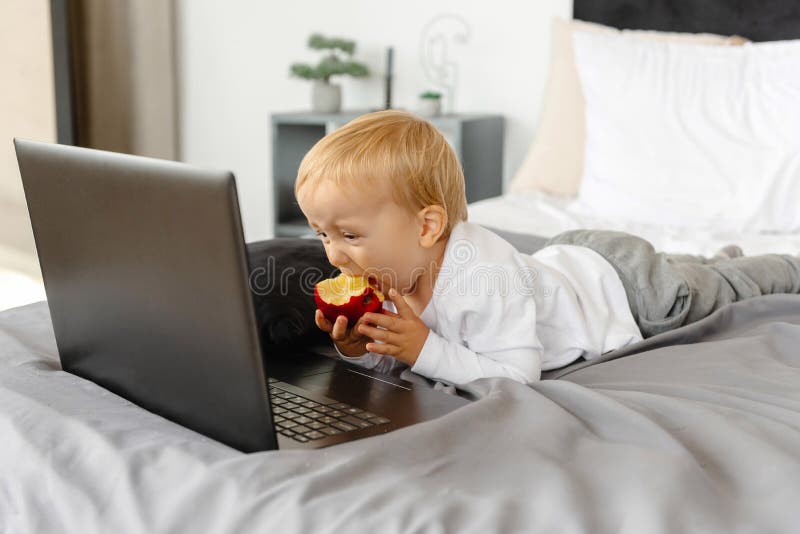 A Child Watches Cartoons on a Laptop and Eats an Apple Stock Image ...